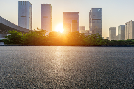 Empty asphalt road and modern city commercial buildings at sunrise in ...