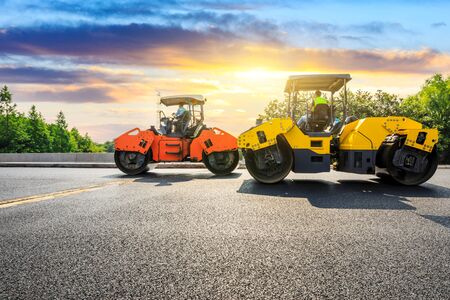 construction machinery and workers laying new asphalt road pavement ...