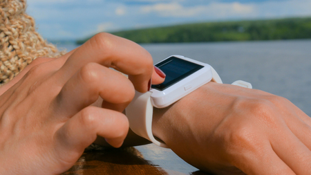 Woman using wearable smartwatch computer device on deck of cruise ship ...