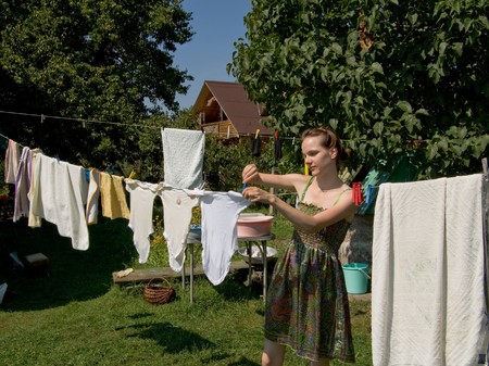 She hangs up the clean clothes on a rope in the garden - Stock Image ...