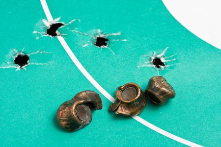 Macro of three squashed bullets on gun target with bullet holes - Stock ...