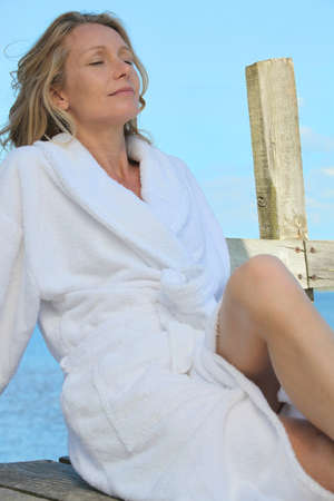 Woman relaxing in the sunshine in a towelling robe - Stock Image ...