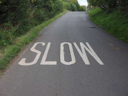Slow sign painted on tarmac on a british road near a school - Stock ...