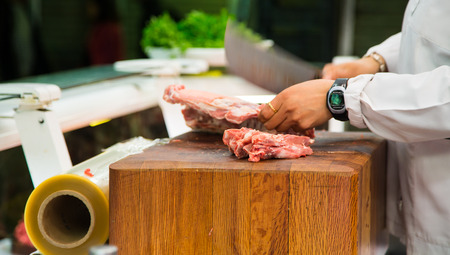 Butcher chopping meat on a wood block with cleaver showing motion blur ...