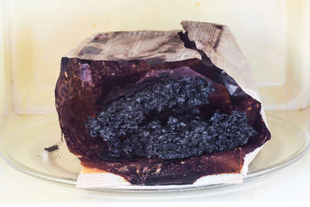 Burnt paper bag with melted and burnt popcorn in the greased and dirty ...