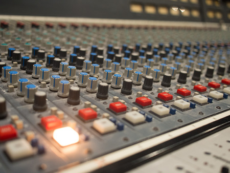 Flashing light on an electronic console with rows of control knobs and ...