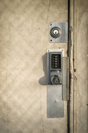 An old, run down wooden door with multiple locks and a keypad entry ...