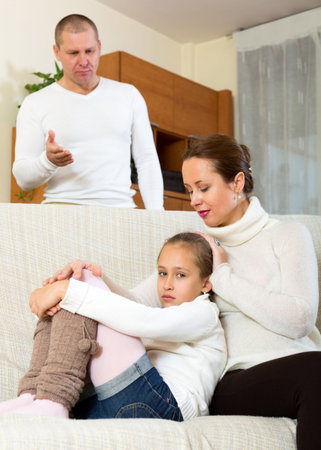 mother gives solace to crying daughter and angry father - Stock Image ...