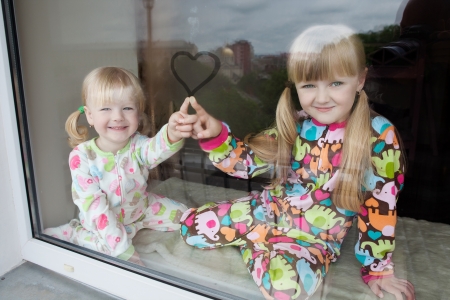 Two girls play at the windows-sill in pyjamas before sleep - Stock ...