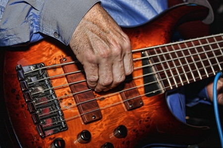Man plays a 6-string electric Fender bass with a gorgeous orange swirl ...