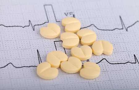 Heart form pills over an electrocardiogram graph - Stock Image - Everypixel