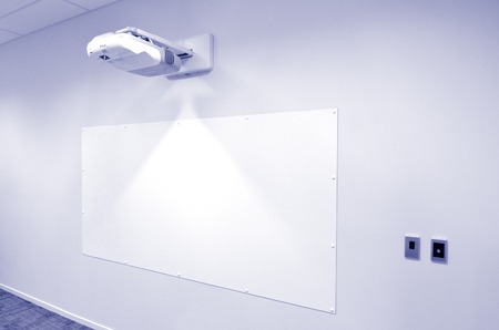 Projection screen with video image projector hung on a wall of meeting ...